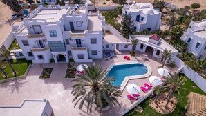 Uma villa moderna com piscina, várias varandas e um jardim bem cuidado.