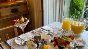 Mesa de café da manhã posta com frutas, suco e flores.