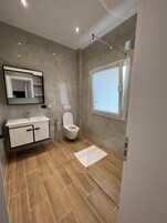 Uma casa de banho moderna com lavatório, sanita e zona de duche.