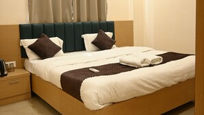 Uma cama bem arrumada com cabeceira, mesa de cabeceira e cortina.