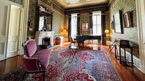 Um quarto com um piano de cauda, lareira, tapete grande e decoração de parede elaborada.
