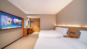 Quarto de hotel com duas camas, uma televisão na parede, um armário de madeira e uma porta para o banheiro.