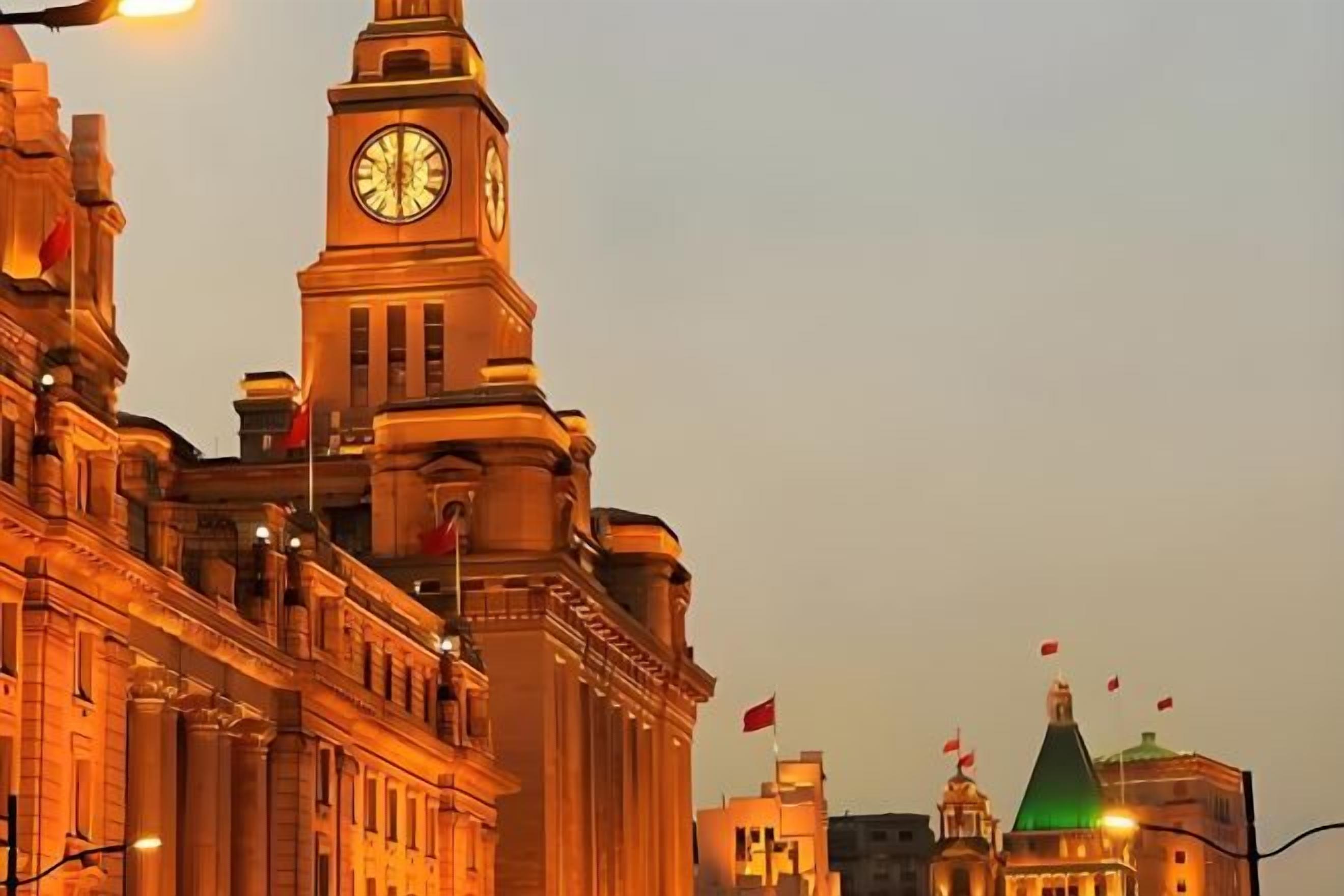 Um edifício histórico com uma torre do relógio imponente e bandeiras.