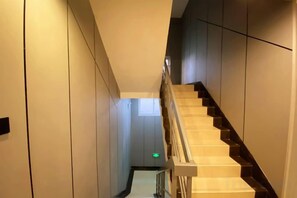 Interior moderno com escada, corrimão e uma fonte de luz no topo.