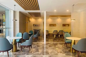 Decoração moderna com mesas e cadeiras redondas, piso de mármore e iluminação pendente.