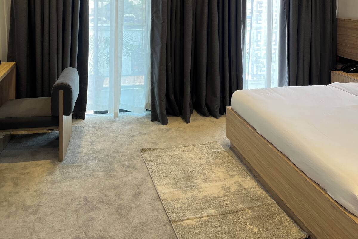 Quarto de hotel moderno com uma cama grande, uma escrivaninha e uma cadeira.