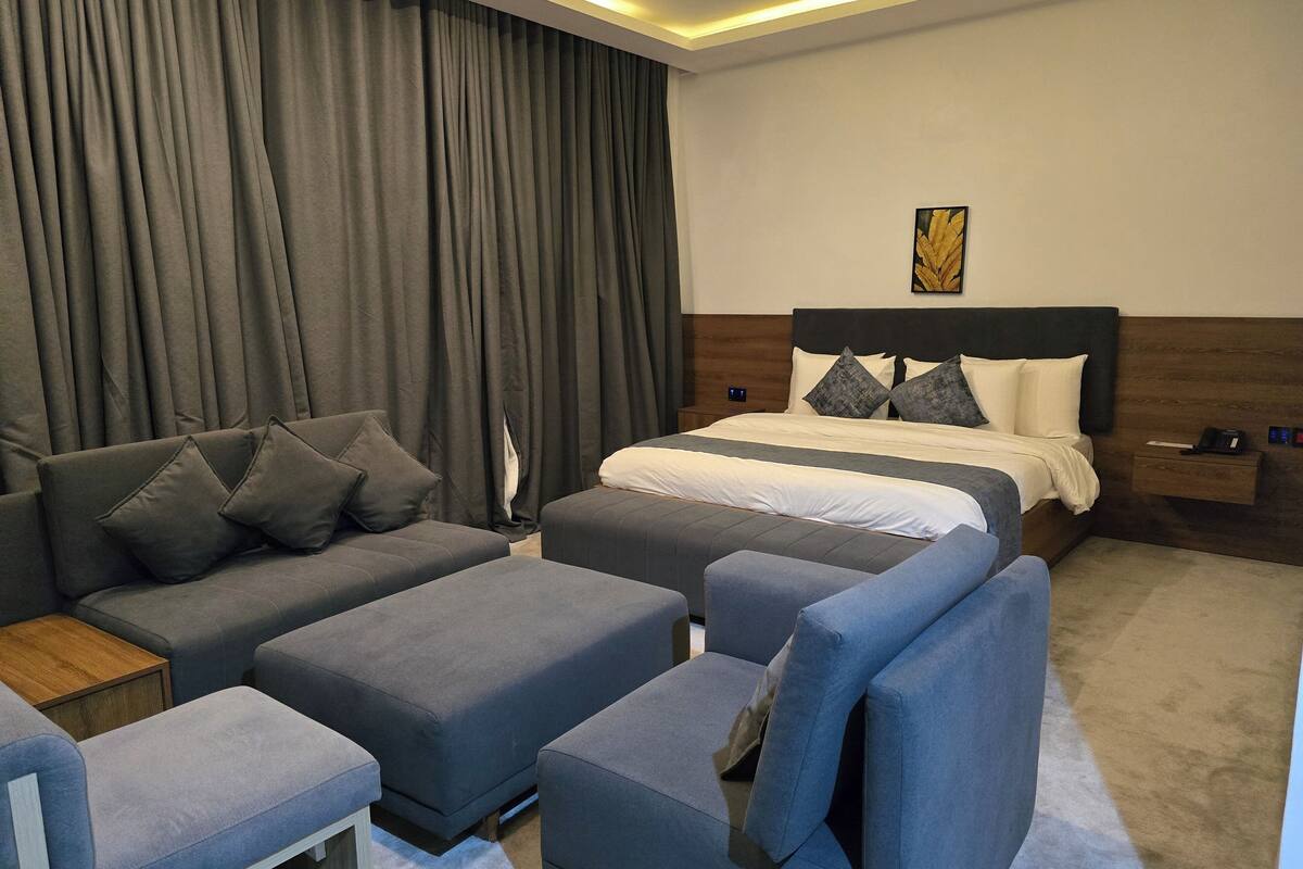 Quarto de hotel moderno com uma cama grande, um sofá e uma mesa pequena.