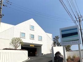 Um edifício moderno com fachada branca e telhado triangular, identificado como HOTEL SOLA.