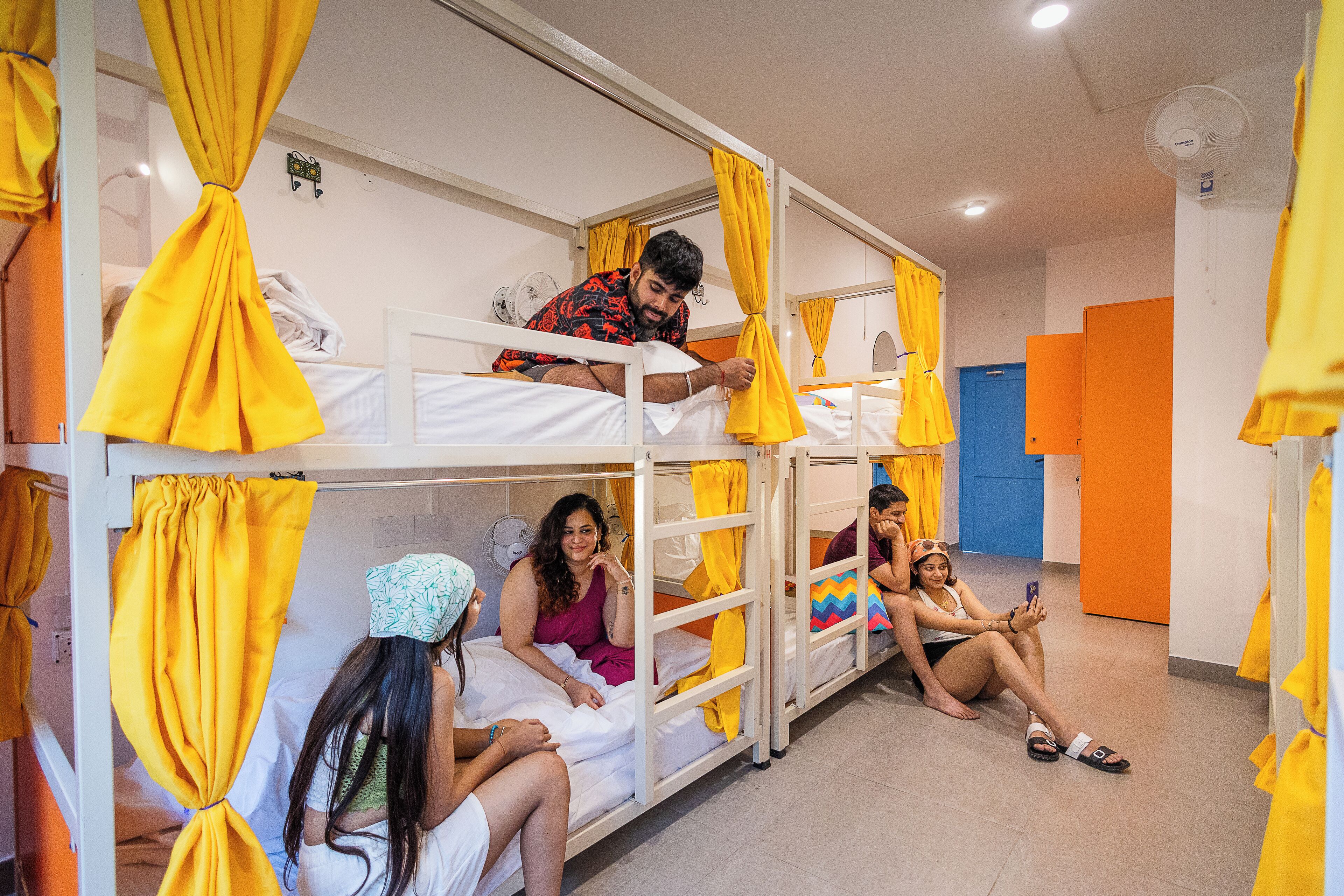 Um dormitório com beliches, cortinas amarelas e um ventilador.
