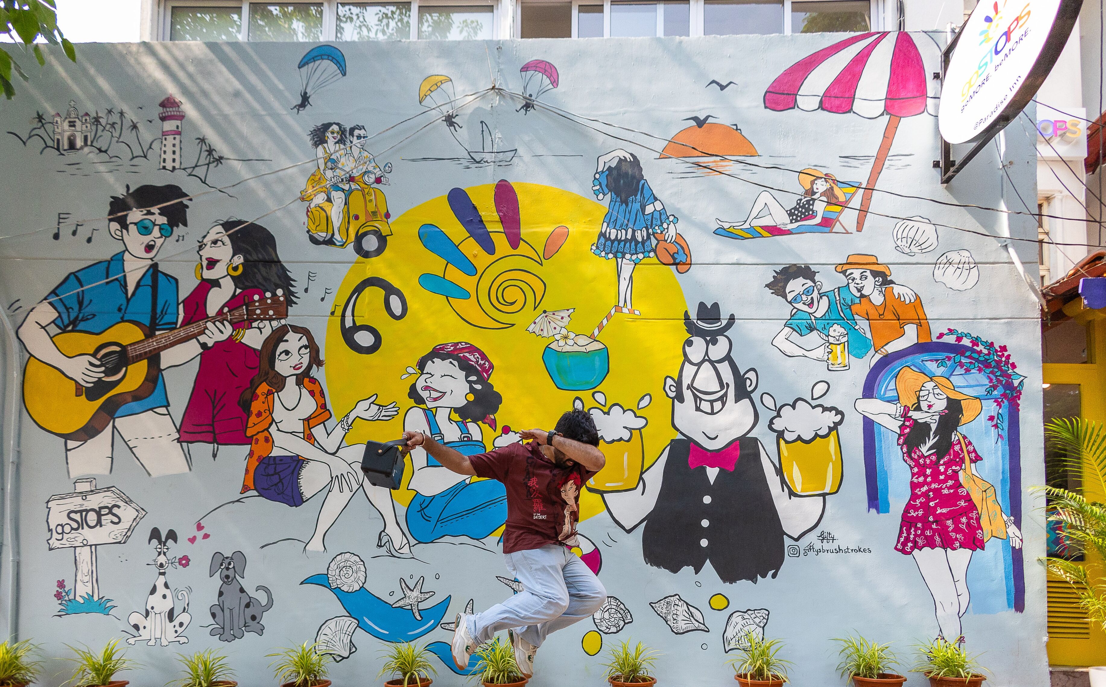 Um mural vibrante com diversos personagens e cenas, incluindo um homem tocando guitarra, uma mulher num vestido vermelho e uma praia com parapente.