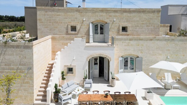 Uma villa de pedra com terraço, área de estar ao ar livre e piscina.