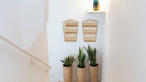 Uma escadaria de madeira leva a um patamar com três vasos de plantas e duas luminárias fixadas na parede.