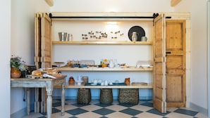 Cozinha com piso xadrez, armários de madeira e diversos utensílios e acessórios de cozinha em prateleiras abertas.