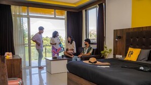 Quarto de hotel moderno com uma cama grande, varanda e vista para o exterior.