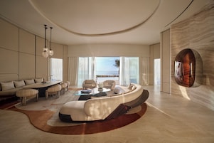 Uma sala de estar moderna com um sofá curvo, uma mesa de centro e vista para o mar.