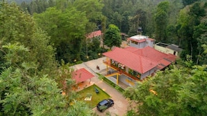 Um edifício de dois andares com telhado vermelho, rodeado por uma floresta densa.