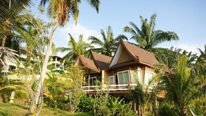 Um resort com várias construções tipo bungalow, rodeado por vegetação exuberante e palmeiras.