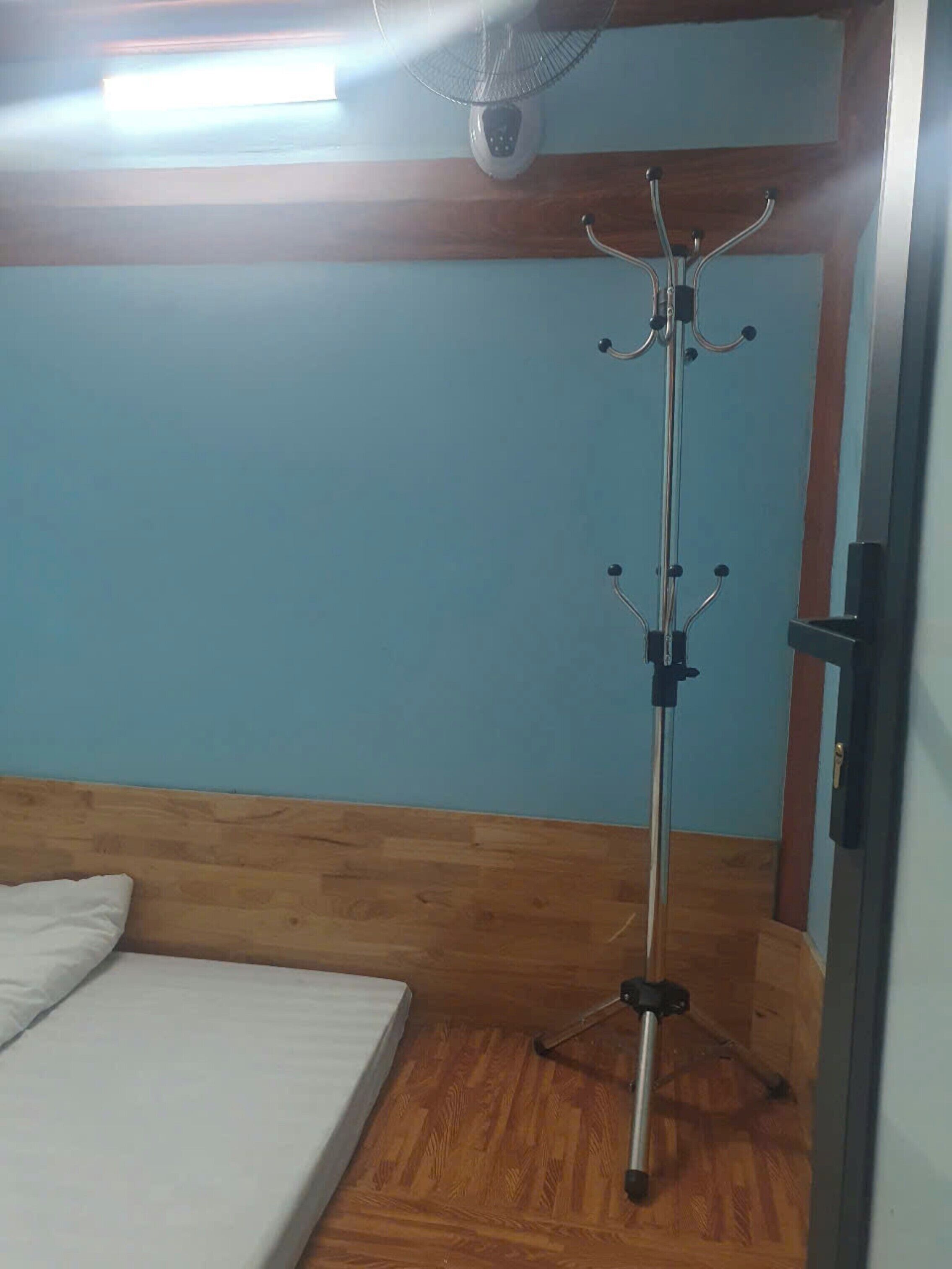 Quarto com cama, ventoinha e cabideiro.