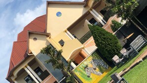 Um edifício de vários andares com telhado de telhas vermelhas, um mural de zebra no andar térreo e um gramado bem cuidado.