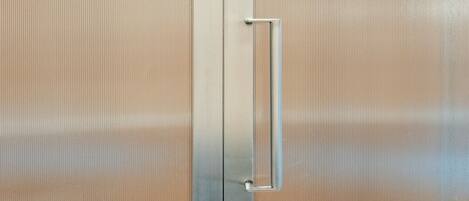 Uma porta metálica com maçaneta, possivelmente de um quarto de hotel ou espaço público.