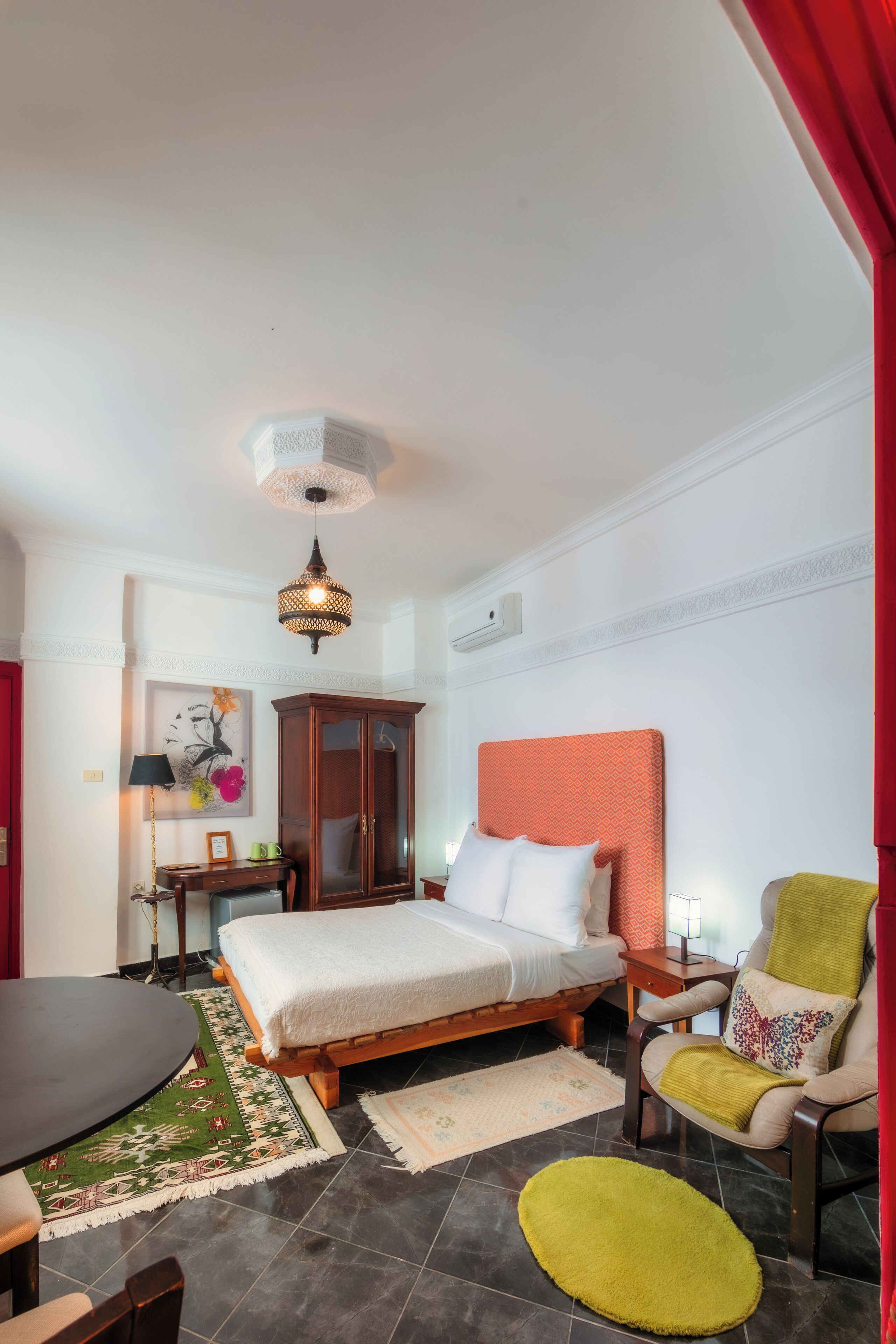 Quarto com cama, cadeira, mesa, armário e luminária pendente.