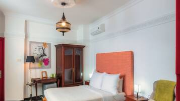Quarto com cama, cadeira, mesa, armário e luminária pendente.