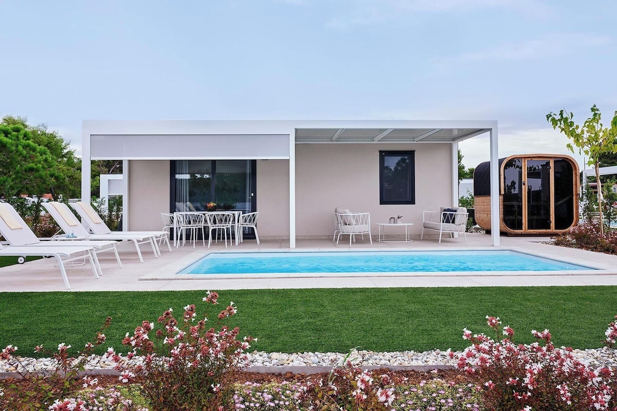 Uma área moderna de piscina ao ar livre com espreguiçadeiras, um espaço de estar coberto e uma estrutura de madeira.