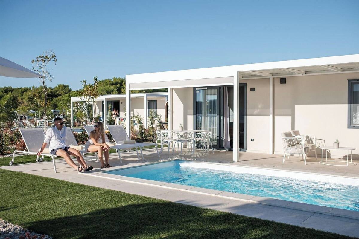 Uma área moderna à beira da piscina, com espreguiçadeiras e piscina.