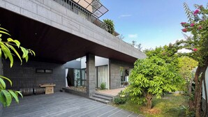 Uma casa moderna com telhado plano, varanda de concreto e um pátio pavimentado.