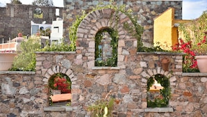Um muro de pedra com três janelas em arco, cada uma com um vaso de planta.