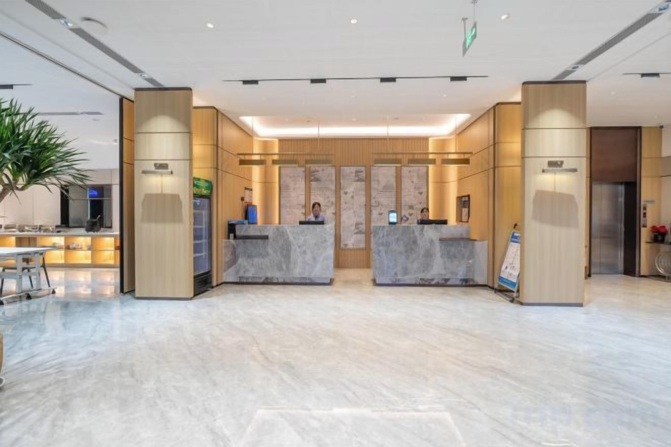Uma área de recepção de hotel com balcões de mármore, um balcão de atendimento e uma grande planta.