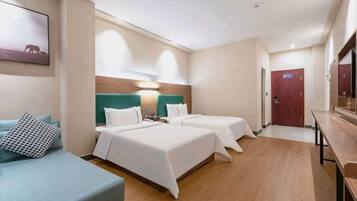 Quarto de hotel com duas camas, um sofá, piso de madeira e uma porta.