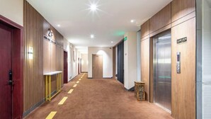Um corredor de hotel com painéis de madeira, piso coberto de carpete e um elevador.