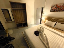 Quarto de hotel com cama, guarda-roupa, espelho e um quadro na parede.