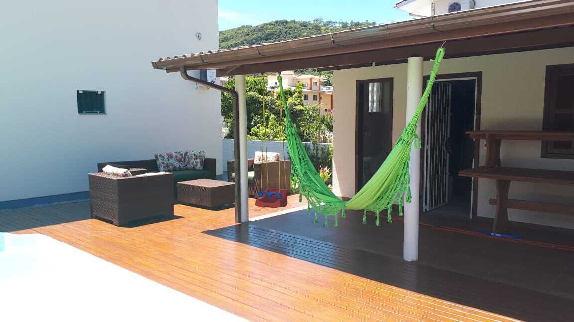 Um pátio externo com uma rede, móveis de madeira e vista para edifícios ao fundo.