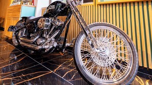 Uma motocicleta em um quarto com painéis de madeira, uma janela e obras de arte emolduradas na parede.