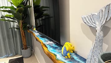 Estante de madeira com um desenho azul e branco, um vaso com planta e uma estatueta de peixe amarelo.