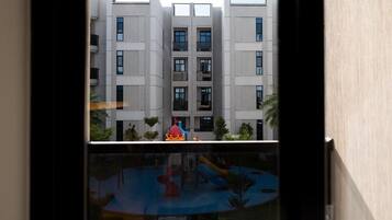 Vista de um prédio de apartamentos moderno com varandas e um parquinho visível embaixo.