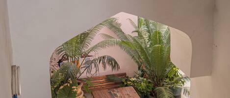 Um quarto com uma mesa de madeira, uma cadeira verde e plantas em vasos.