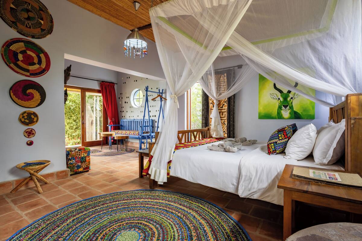 Quarto com cama, mesa, cadeira, cadeira suspensa e tapete colorido feito à mão.