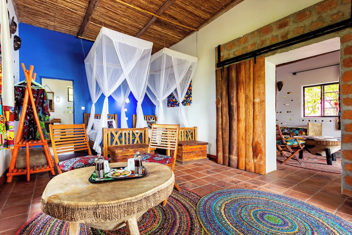 Um quarto com uma mesa redonda de madeira, tapetes trançados coloridos e uma parede azul.