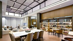 Uma sala de estar espaçosa e moderna, com uma mesa de jantar grande, assentos confortáveis e uma estante bem organizada.