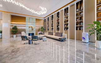 Um lobby moderno com piso de mármore, área de estar e estantes de livros.