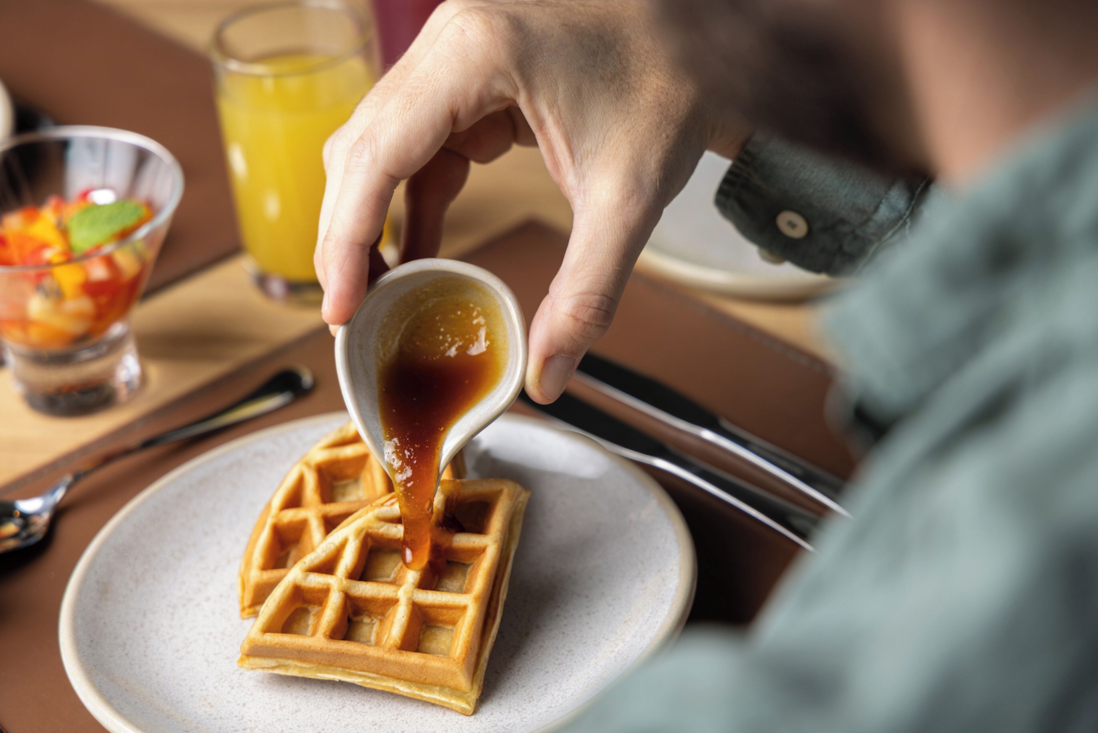 Alguém despejando xarope em um waffle.