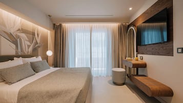 Quarto de hotel moderno com cama grande, um banco embutido, televisão de tela plana e uma janela ampla com cortinas leves.