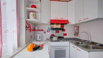 Um frigorífico, um forno, uma placa de cozinha, uma cafeteira/bule