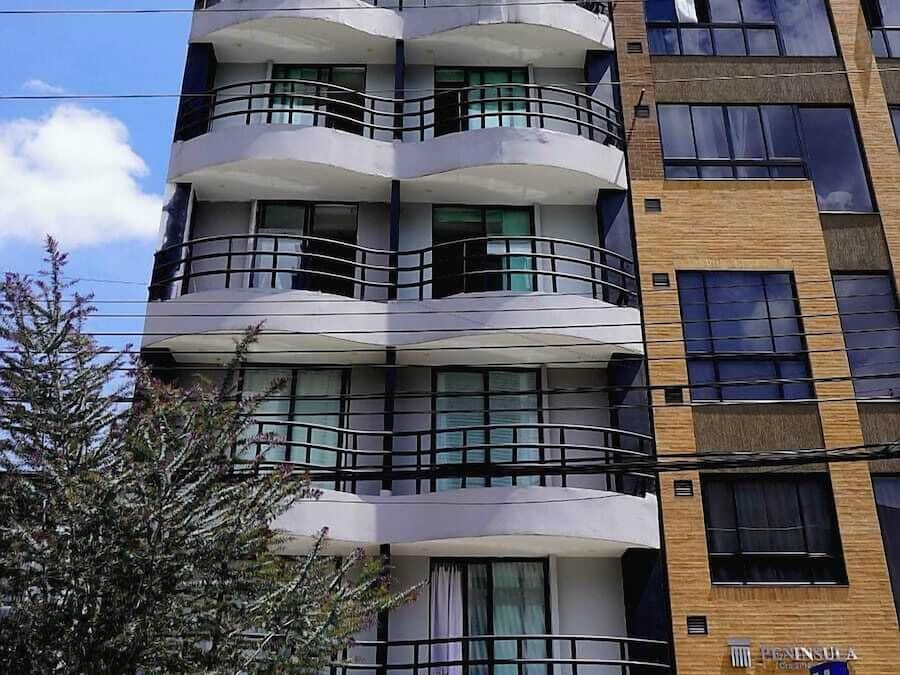 Um edifício com vários andares, varandas, um relógio e sinalização com a inscrição