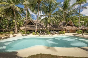 Um resort com uma piscina grande, palmeiras e cabanas com telhado de palha.