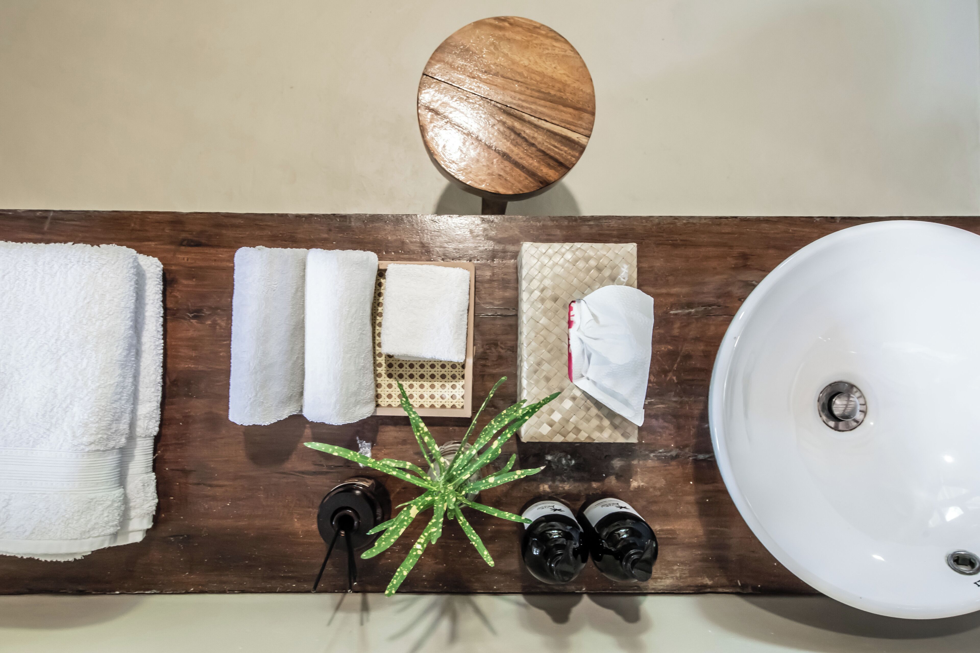Casa de banho com toucador de madeira, lavatório branco e diversos artigos de higiene pessoal.