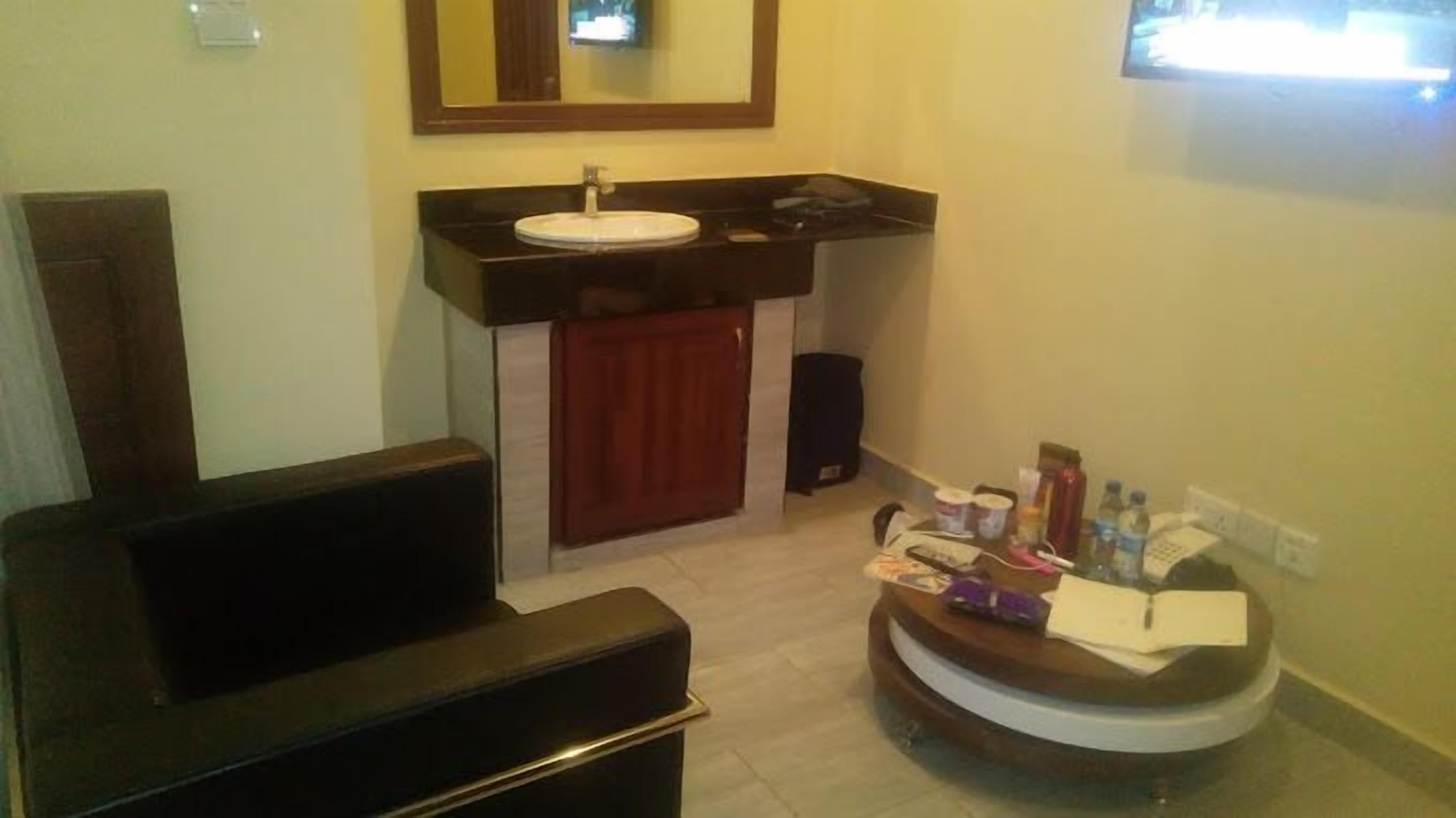 Casa de banho com lavatório, espelho e artigos de higiene pessoal sobre um balcão.